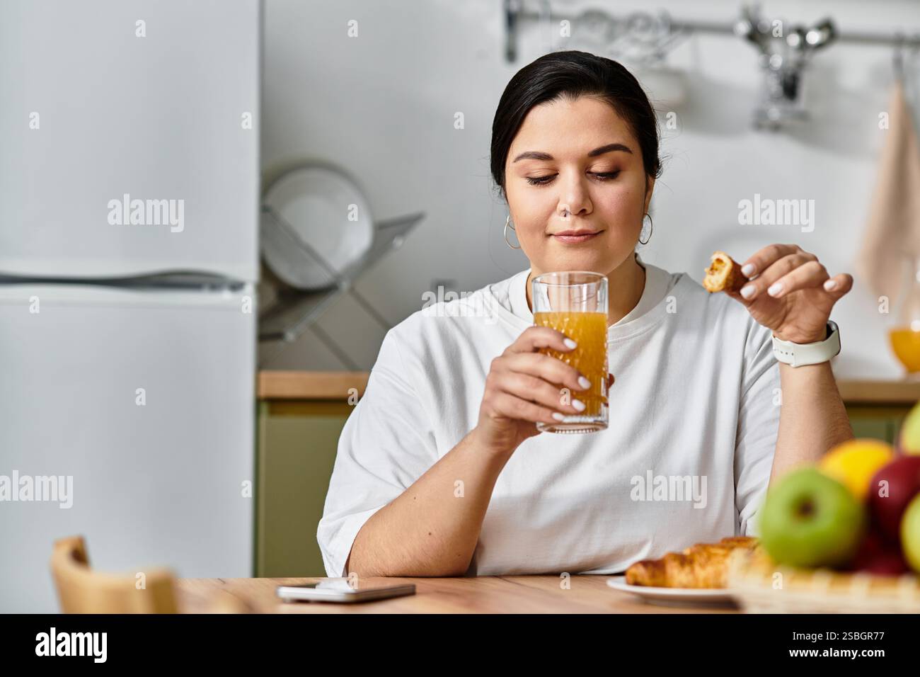 A young plus sized woman savors orange juice while enjoying a delicious ...