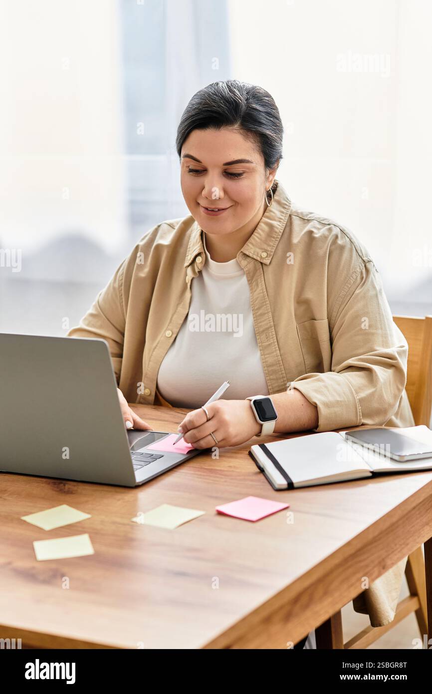 A young plus sized woman sits at her desk, confidently using her laptop ...