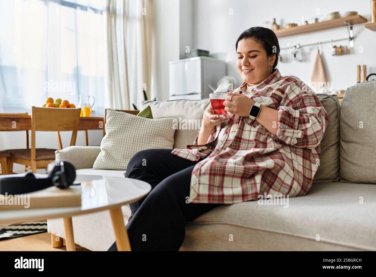 A beautiful young plus sized woman relaxes on a soft couch while ...