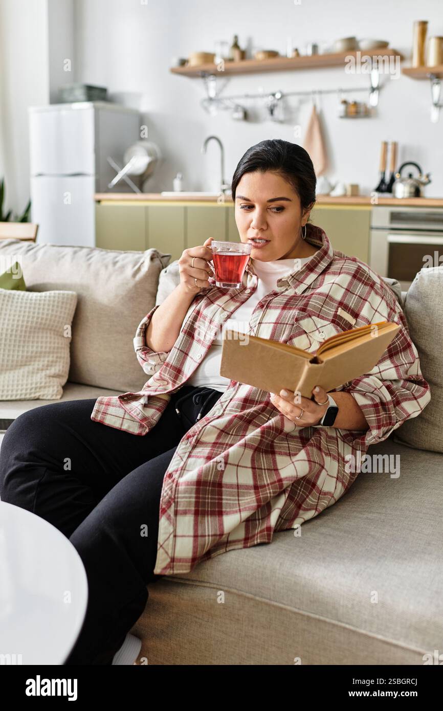 A young plus sized woman relaxes on a cozy couch, sipping tea while ...