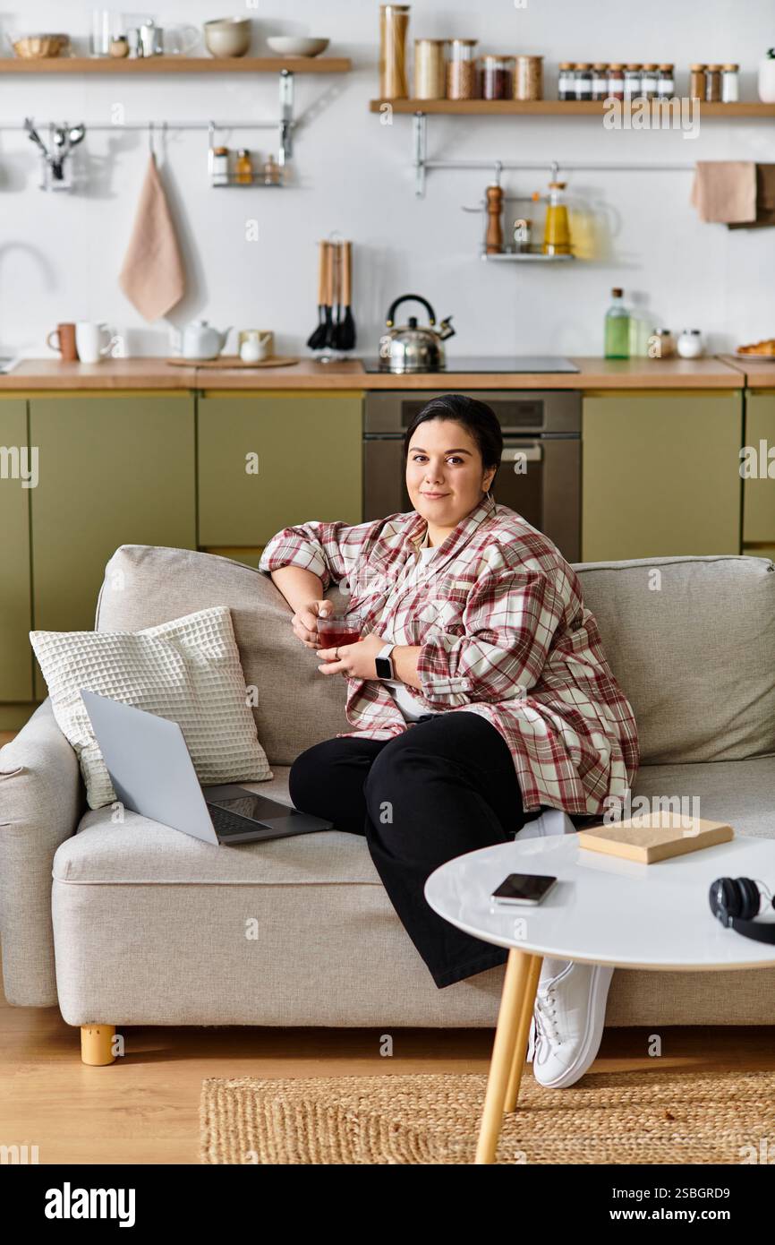 A plus sized woman relaxes on a couch, engaging with her laptop in a ...