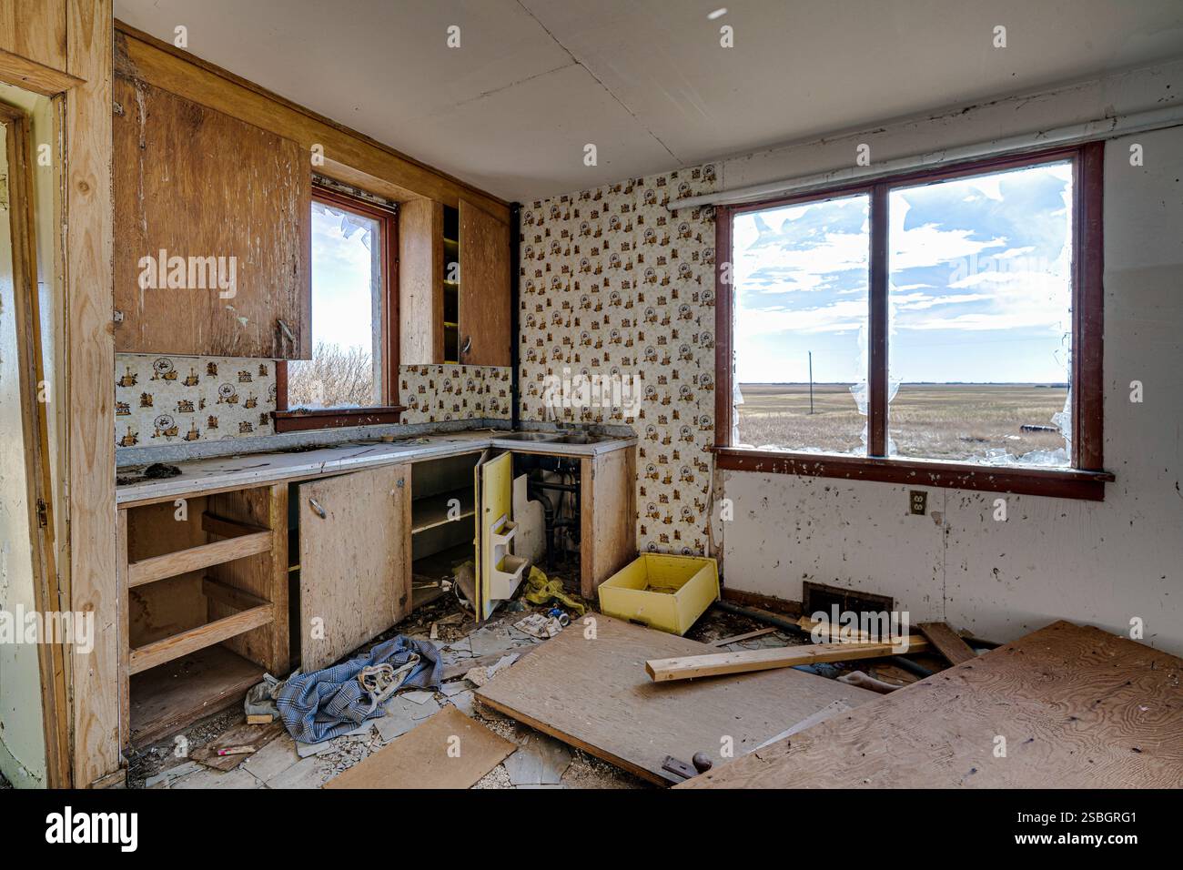 A kitchen with a yellow trash can and a broken window. The kitchen is ...