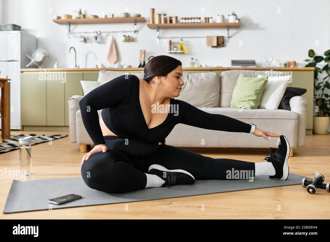 A beautiful plus sized woman engages in stretching exercises on a yoga ...