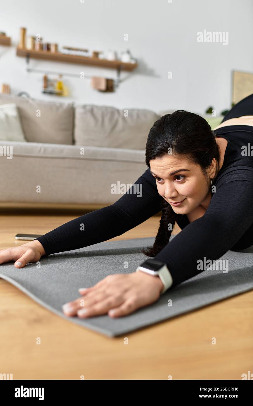 A young plus sized woman stretches on a yoga mat, promoting body ...