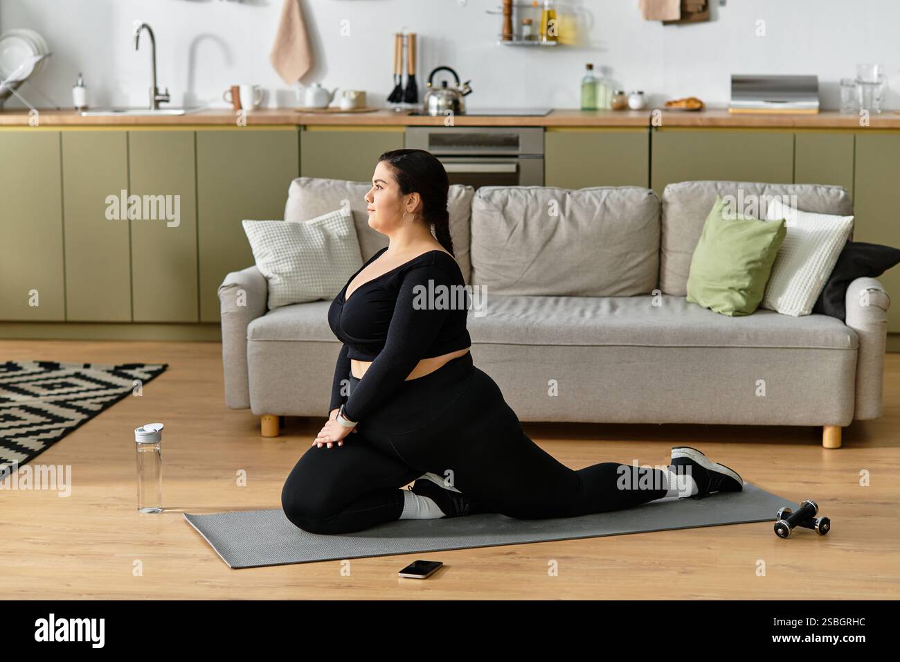 A young plus sized woman stretches elegantly on a yoga mat in her ...