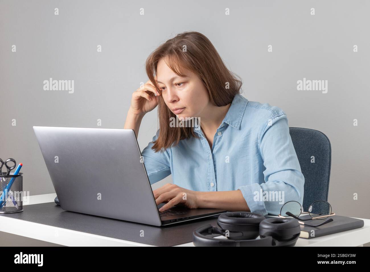 A woman typing on the keyboard using laptop, looking at PC screen ...