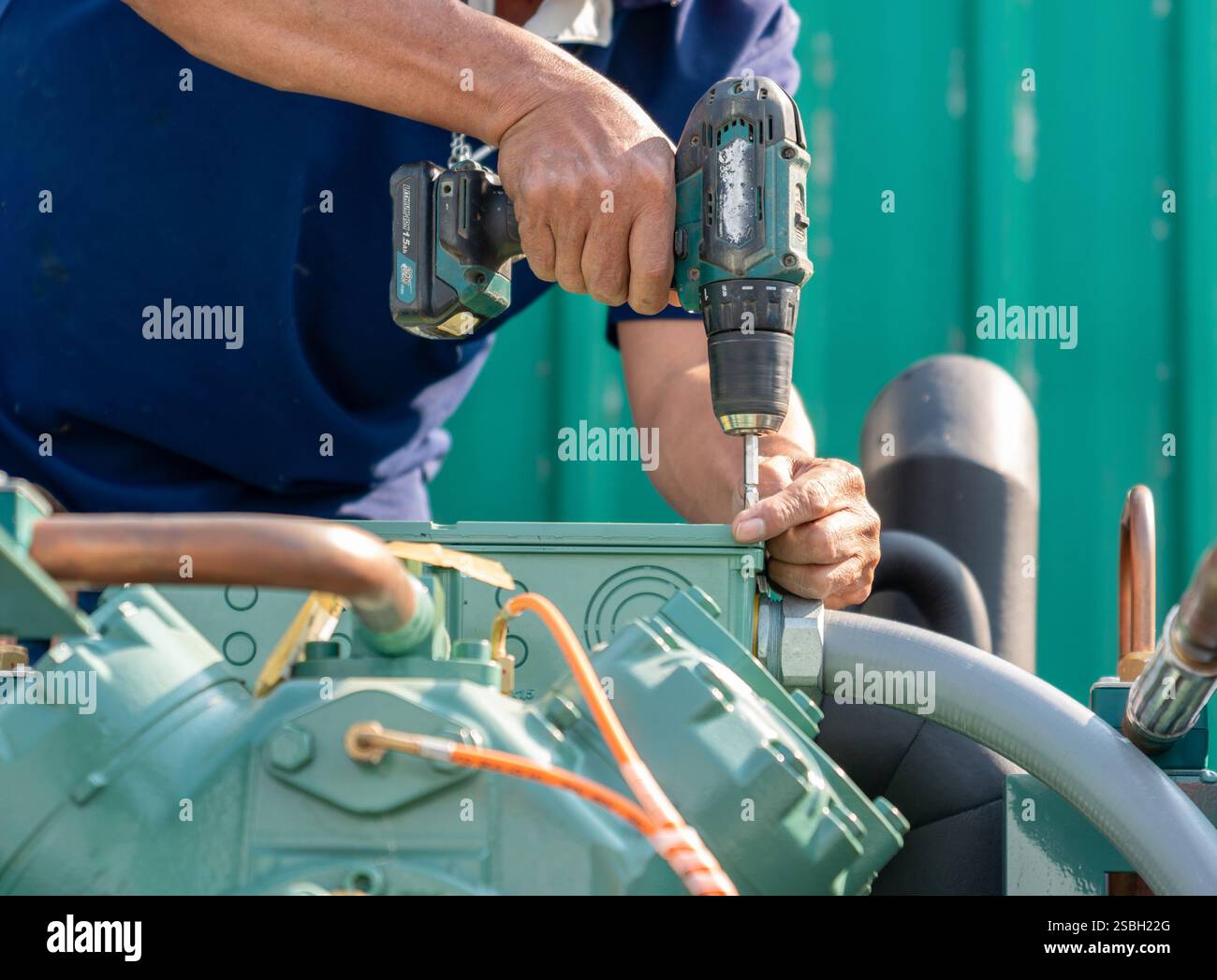 The technician uses a cordless screwdriver to tighten nut cover ...