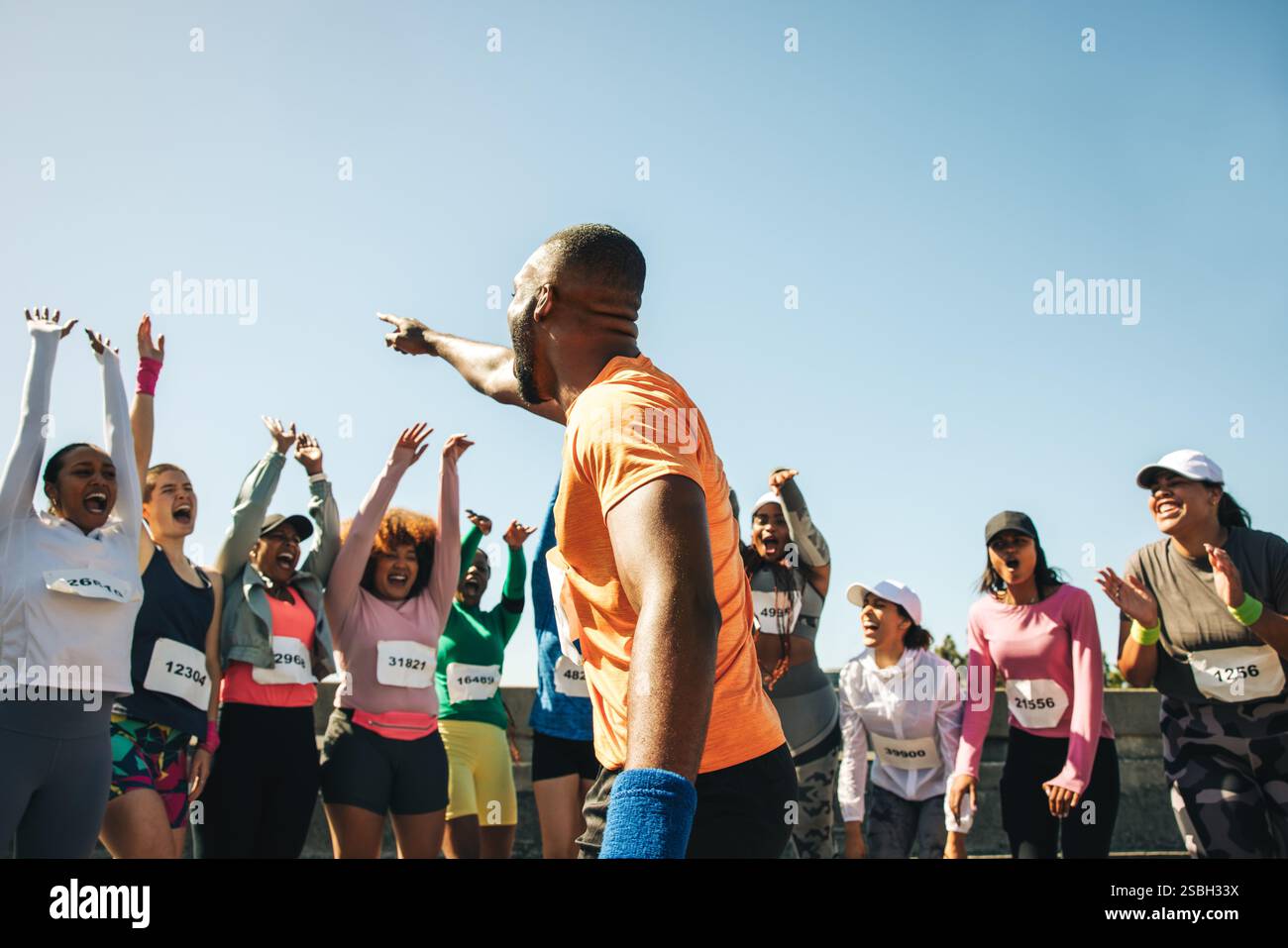 A group of enthusiastic runners gathers at the starting line of a ...
