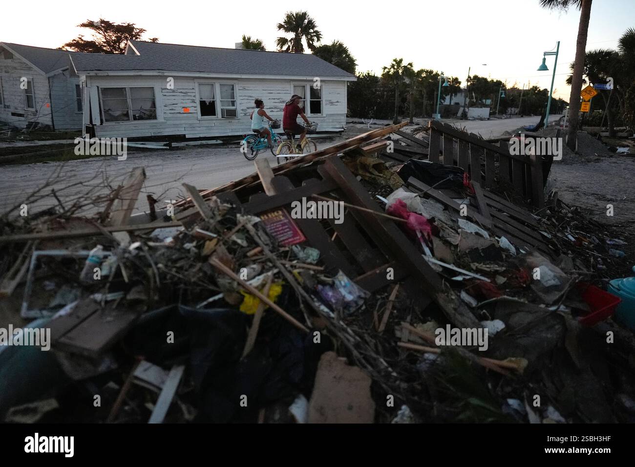 FILE - People bike past damaged homes and debris left by Hurricane ...