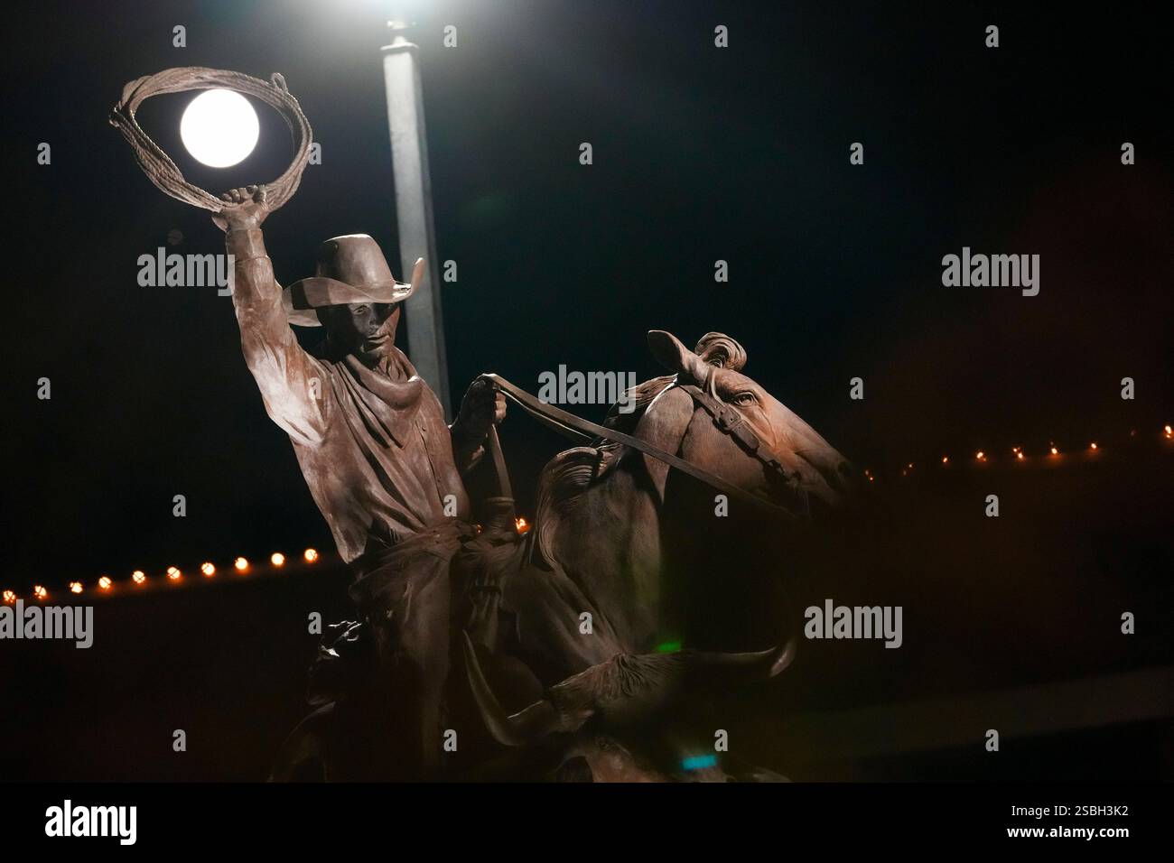 The full moon is seen through the lasso of statue depicting a cowboy ...