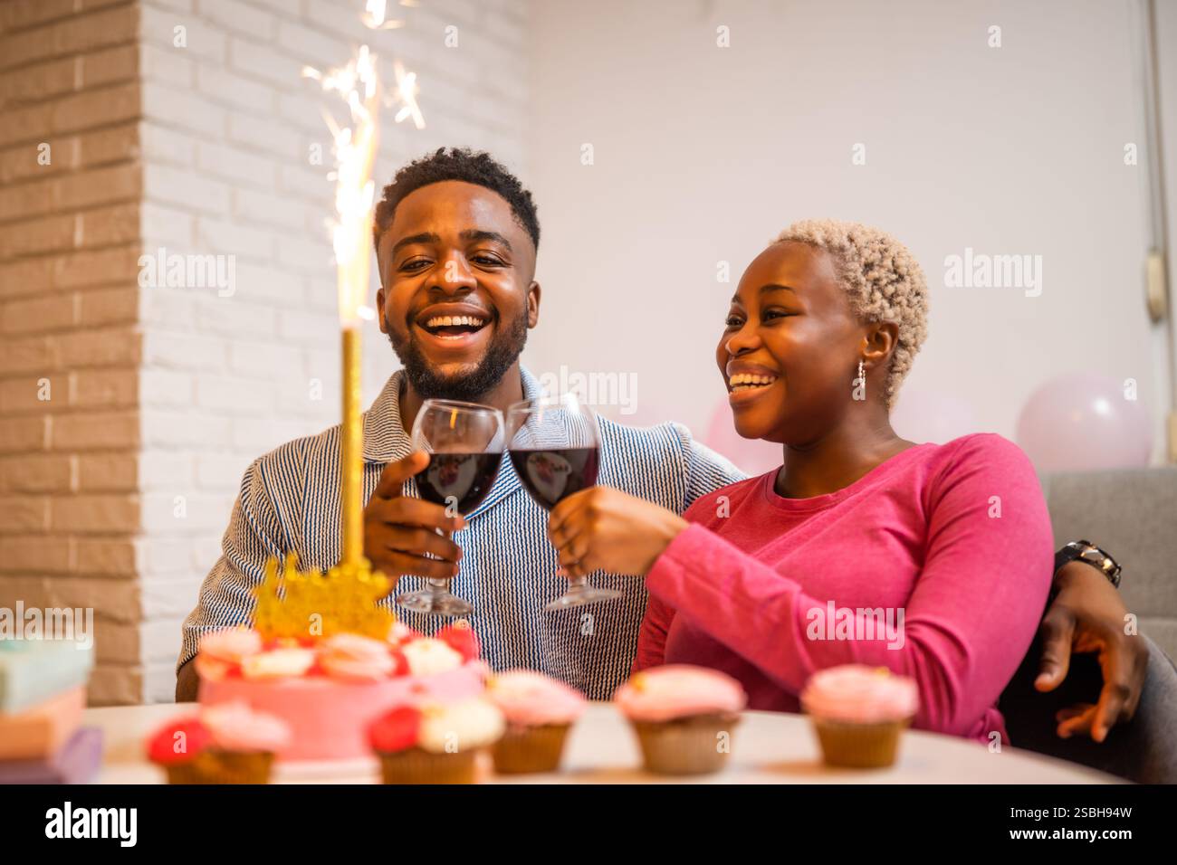 Happy young couple celebrating woman's birthday at home. They are ...
