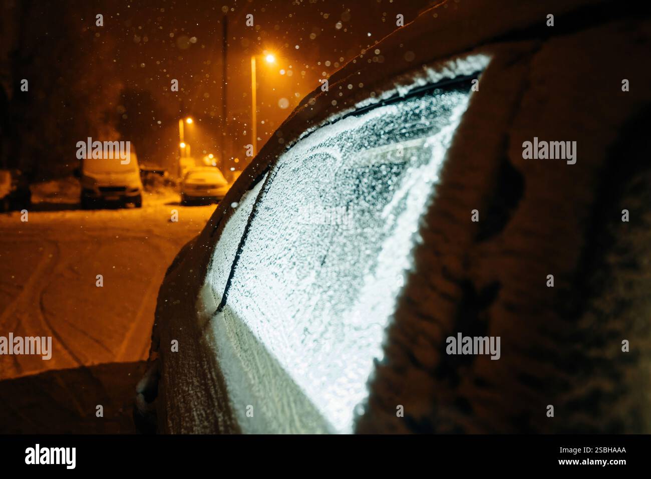A frosted car window glowing with interior light on a snowy night ...