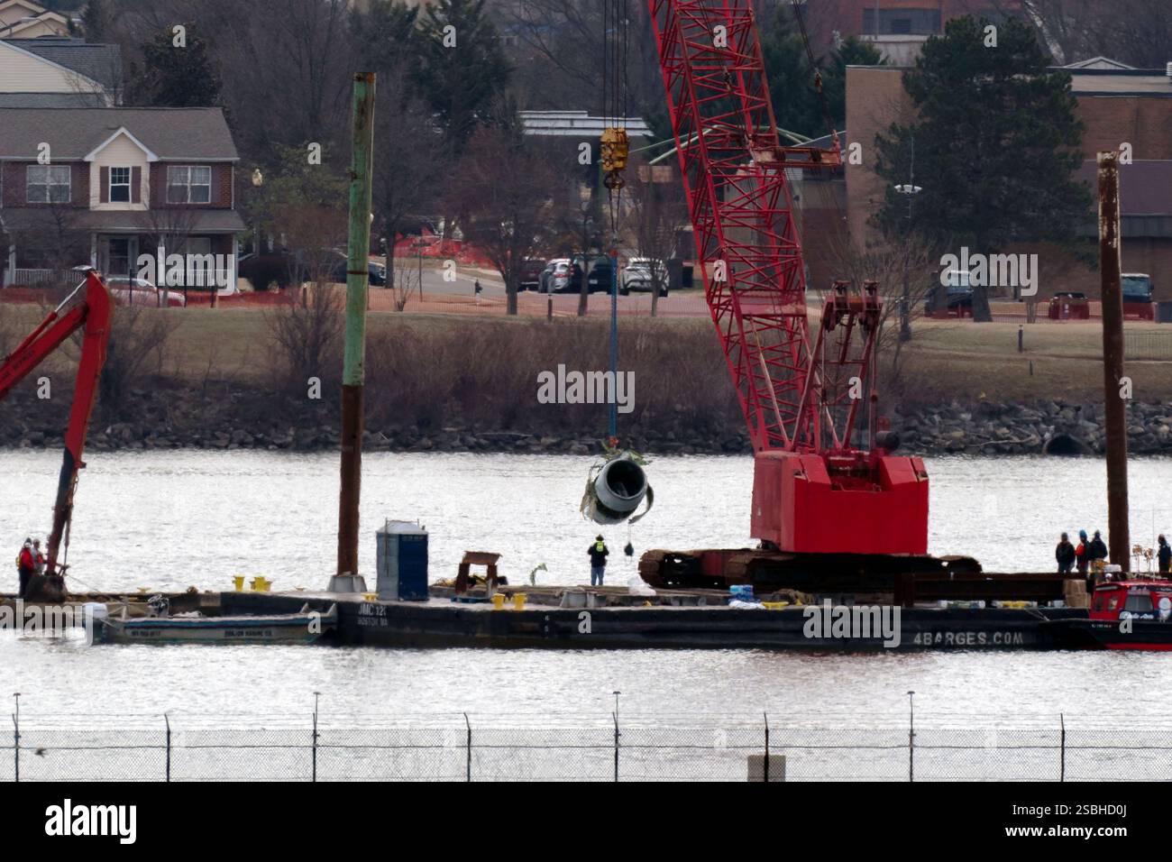 Rescue and salvage crews pull up a plane engine as cranes work near the wreckage of an American ...