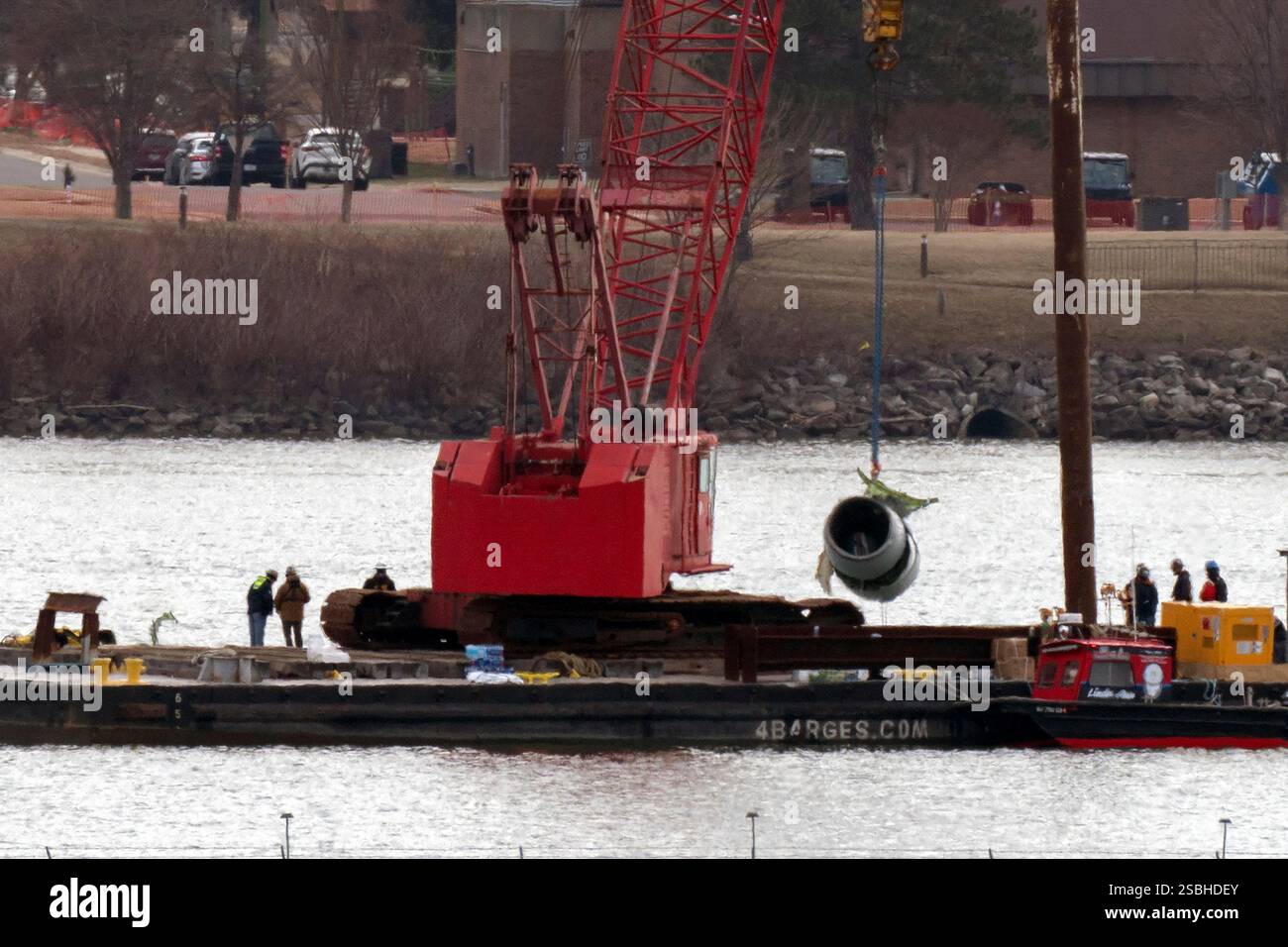 Rescue and salvage crews pull up a plane engine as cranes work near the wreckage of an American ...