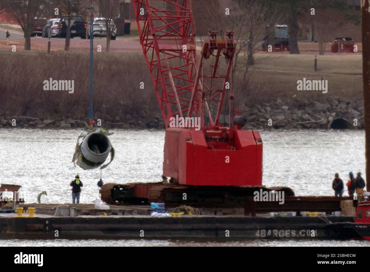 Rescue and salvage crews pull up a plane engine as cranes work near the wreckage of an American ...