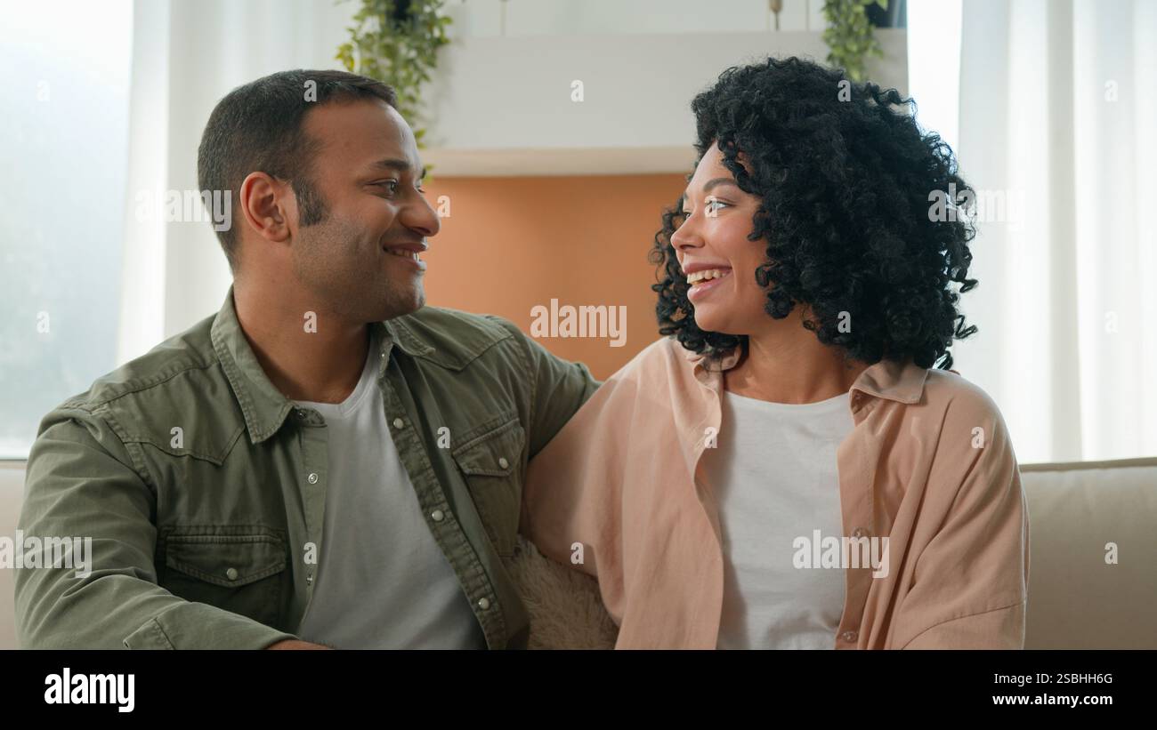 Happy parents African American mother father embrace cuddle on couch ...