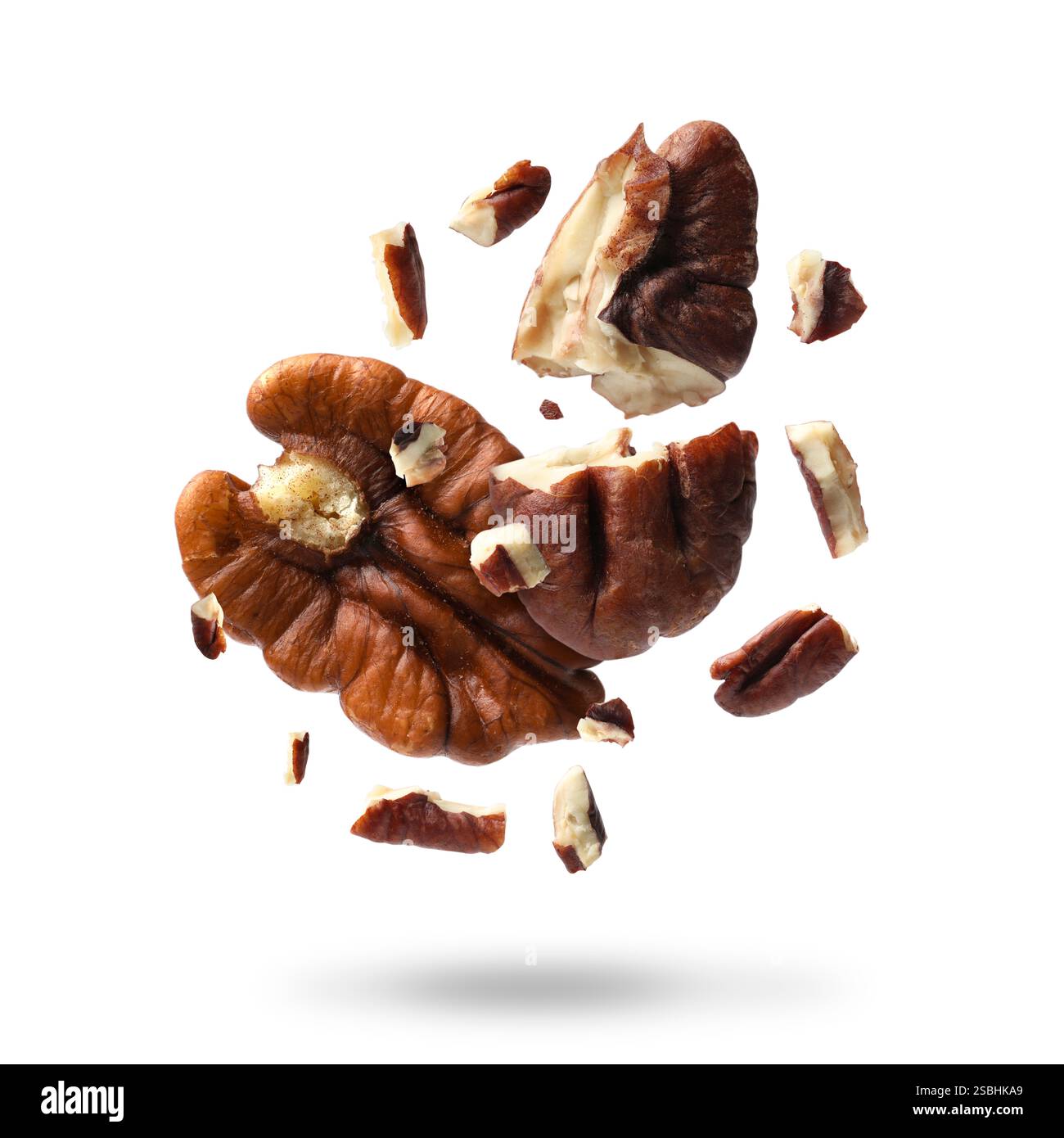 Broken pecan nuts in air on white background Stock Photo - Alamy