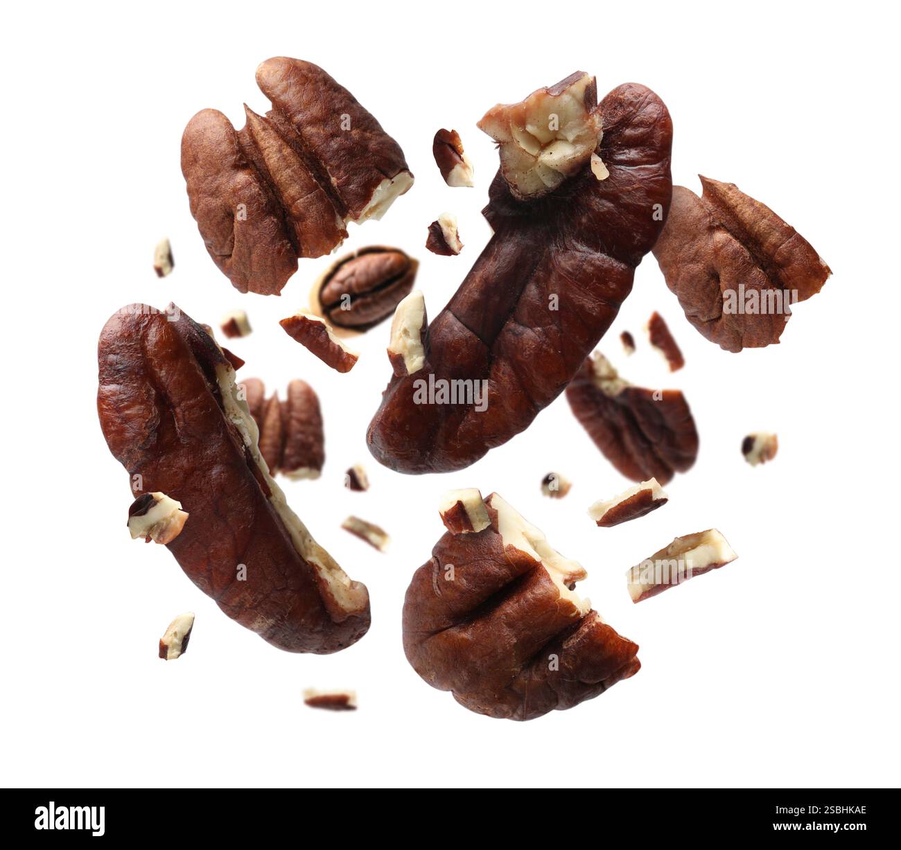 Broken pecan nuts in air on white background Stock Photo - Alamy