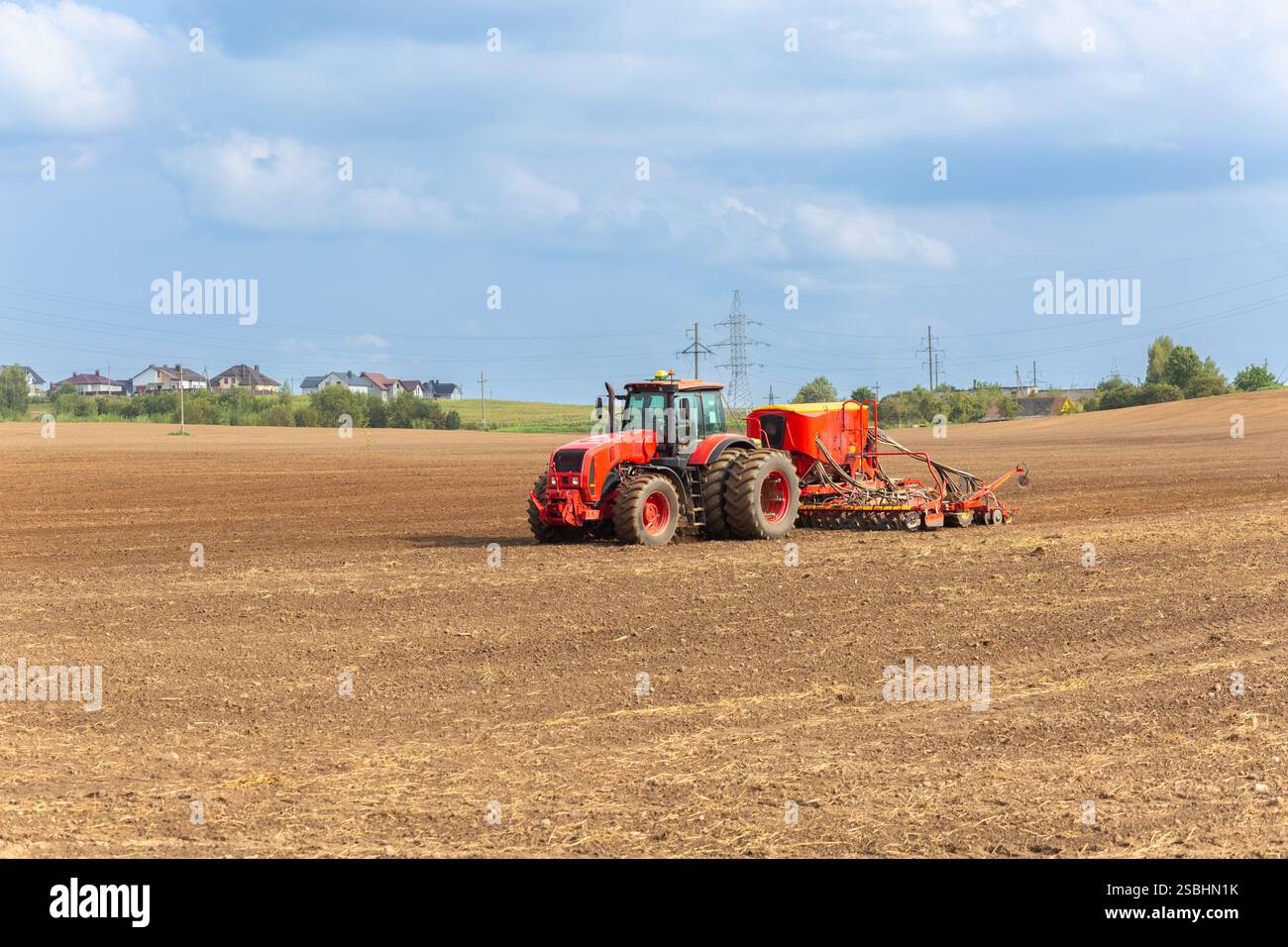A tractor with a pneumatic seeder attached sows seeds while applying ...