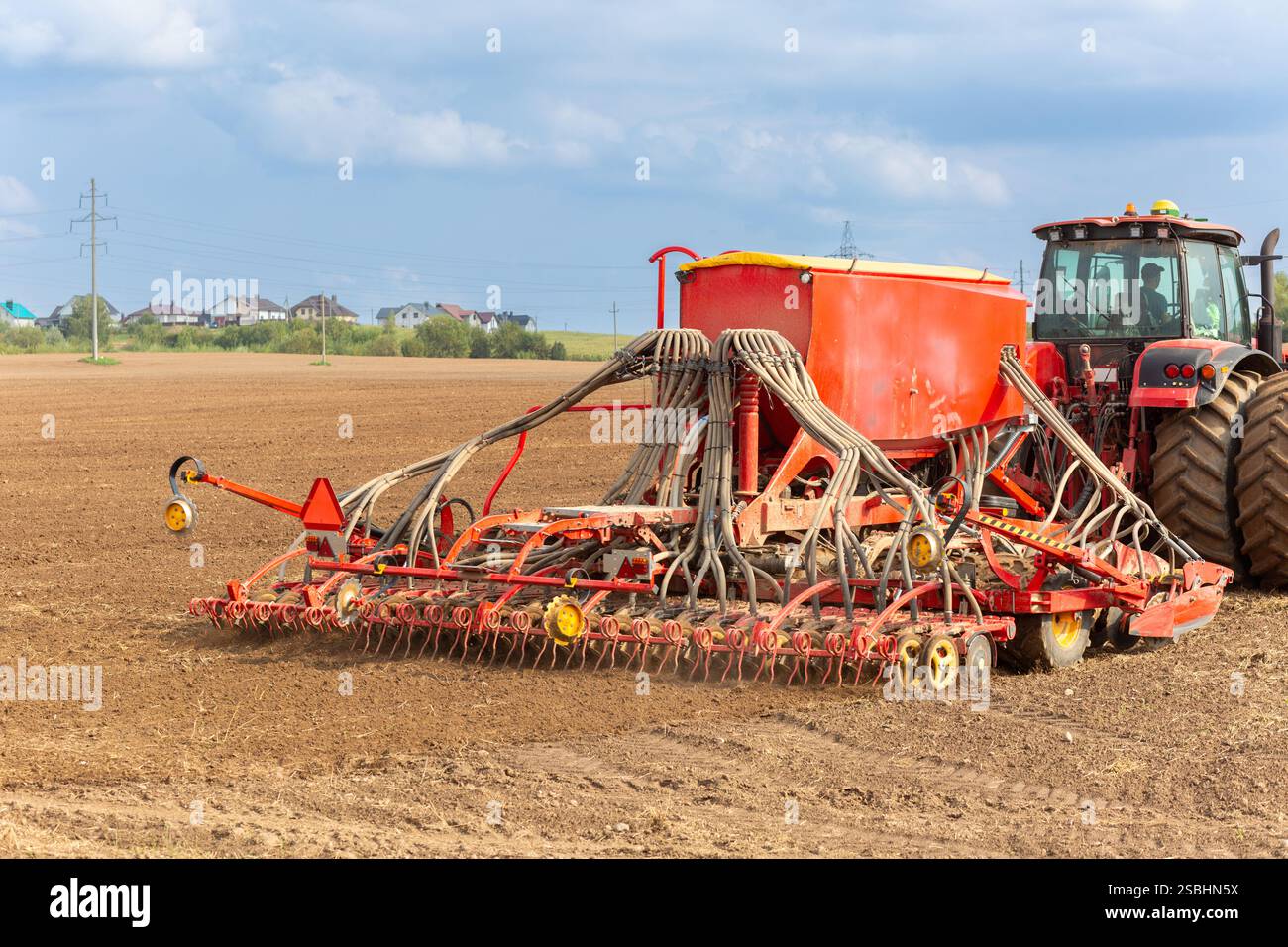 A tractor with a pneumatic seeder attached sows seeds while applying fertilizers to the soil. A ...