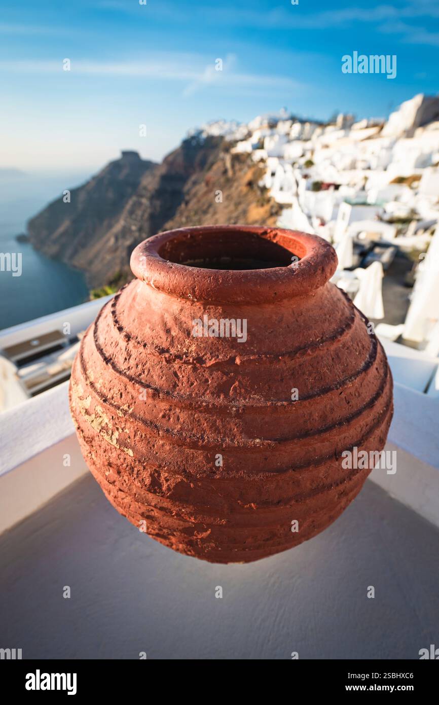 A large round terracotta flower pot in front of the white houses of ...