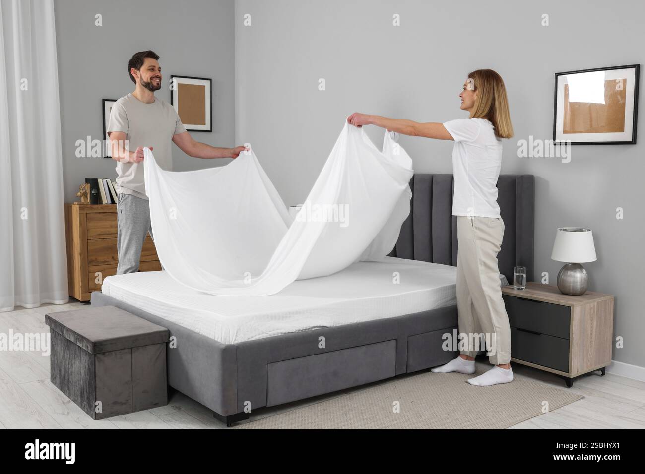 Couple changing bed linens in room. Domestic chores Stock Photo - Alamy