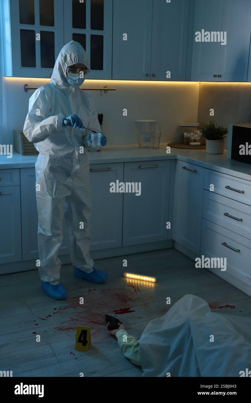 Forensic expert collecting bullet shell into container near dead body ...