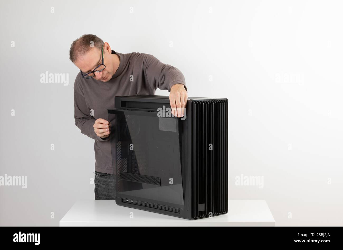 Man removing tempered-glass left panel from PC case, empty big tower ...