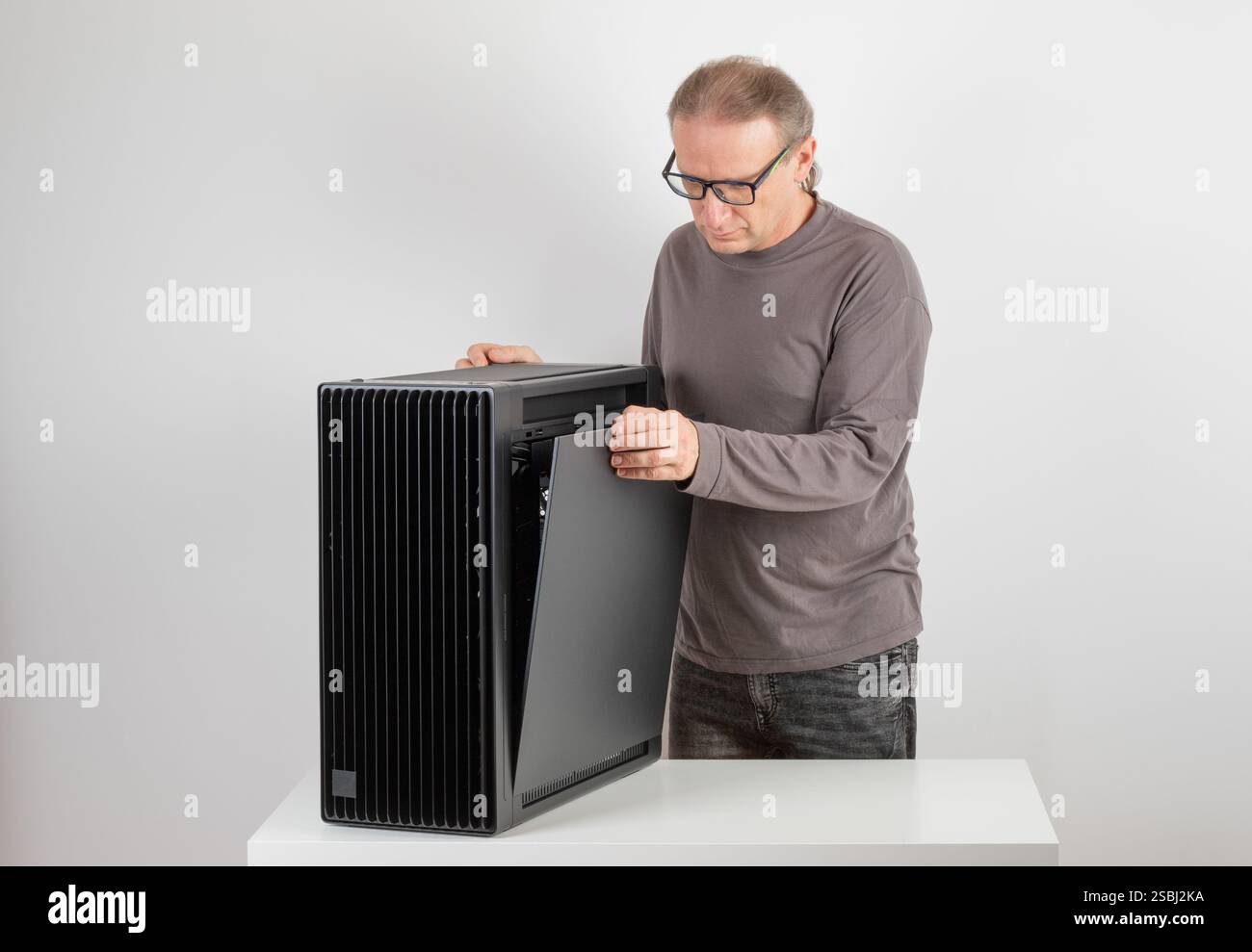 Man removing metal right panel from PC case, empty big tower, chassis ...