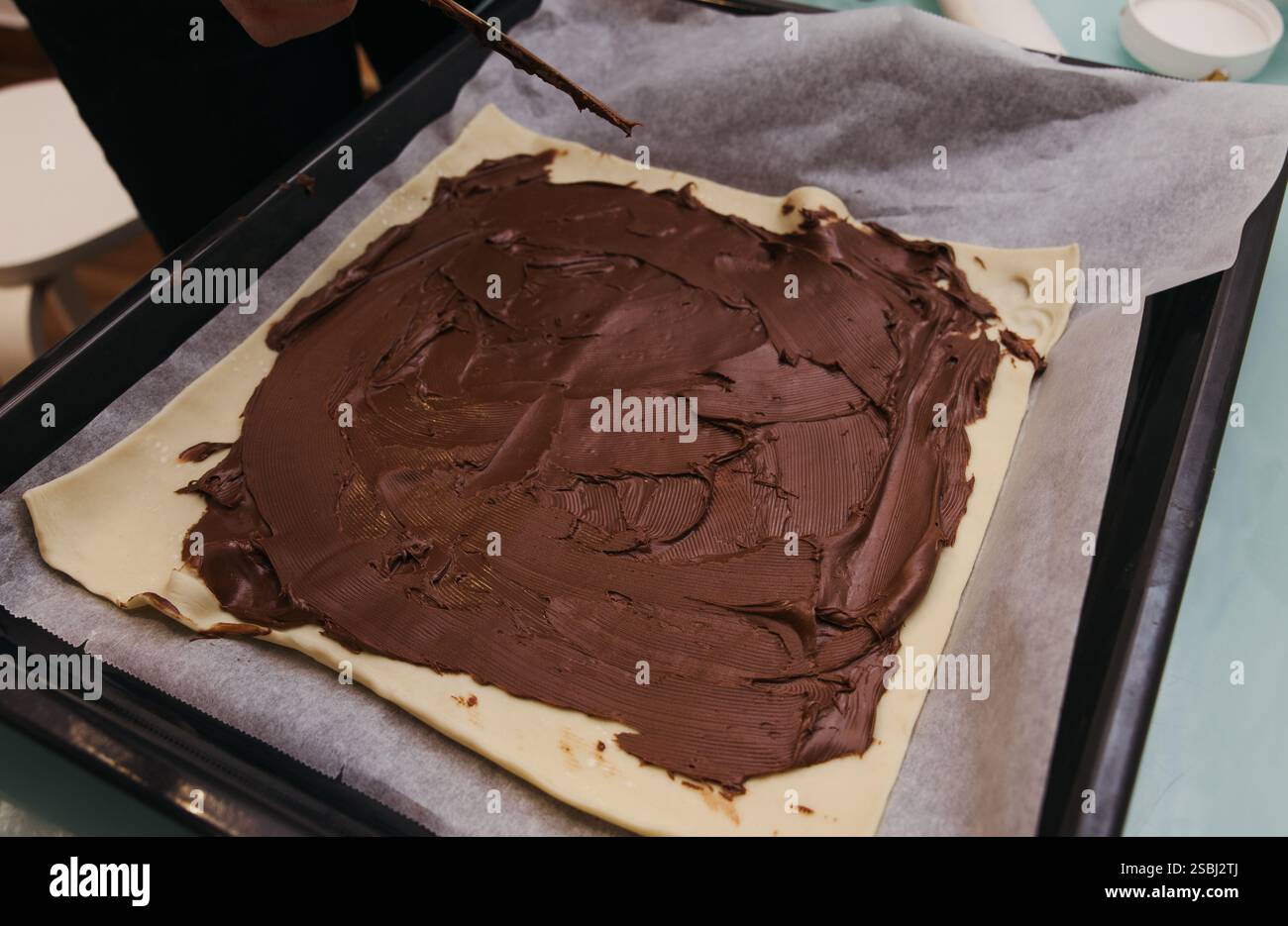 Raw puff pastry covered with chocolate spread, ready for baking Stock ...
