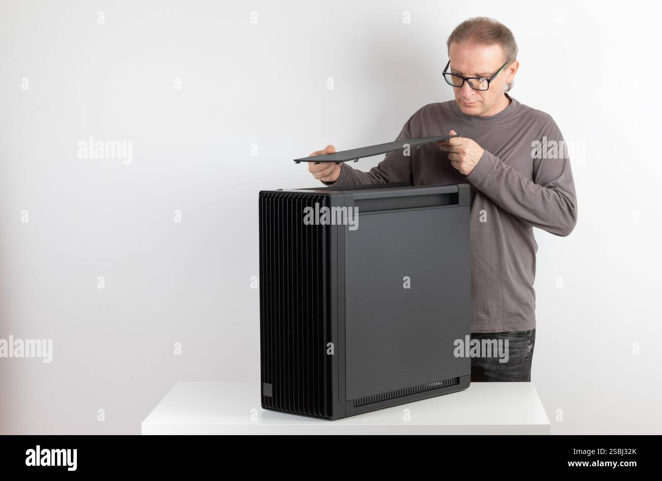 Man removing top panel with dust filter from PC case, empty big tower ...