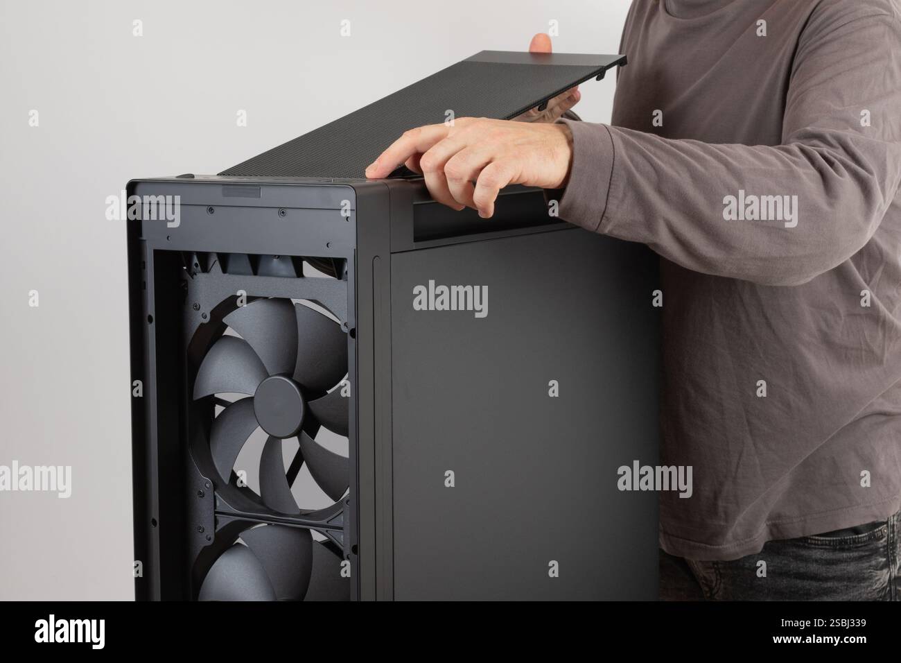 Man installing top panel with dust filter from PC case, empty big tower ...