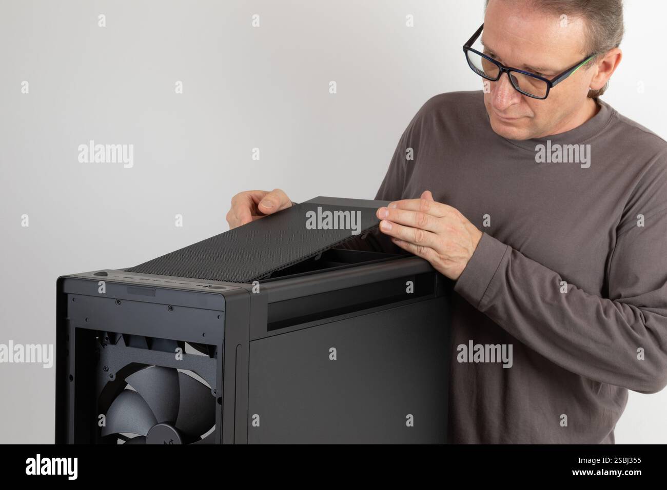 Man installing top panel with dust filter to PC case, empty big tower ...