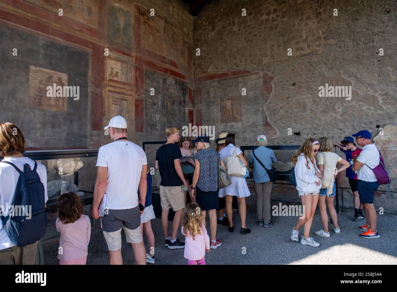 Tourists view body casts in the Macellum or marketplace, Building VII.9.7, in the ancient Roman ...