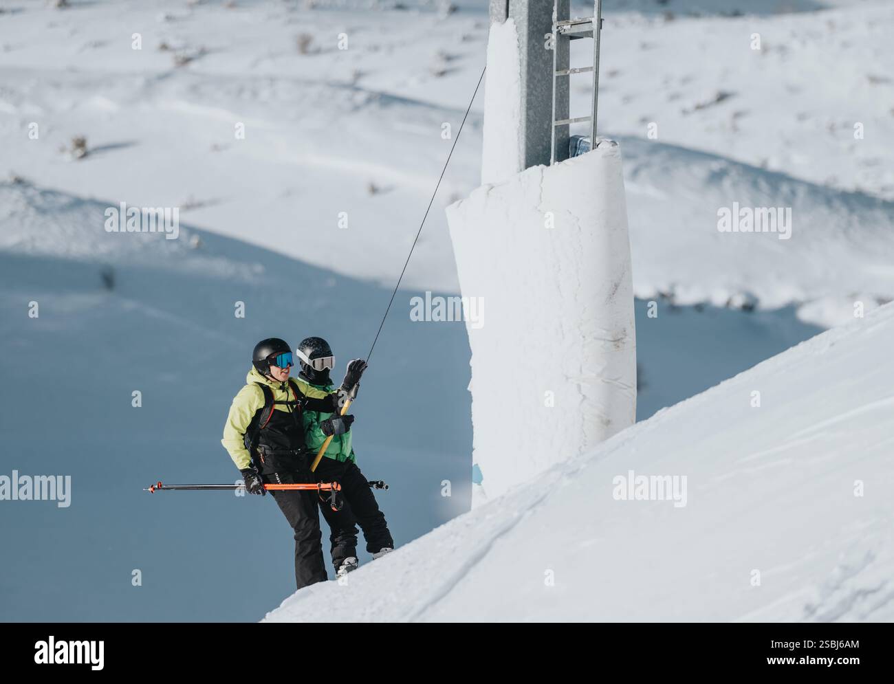 Two skiers riding a ski lift on a snowy mountain slope Stock Photo - Alamy