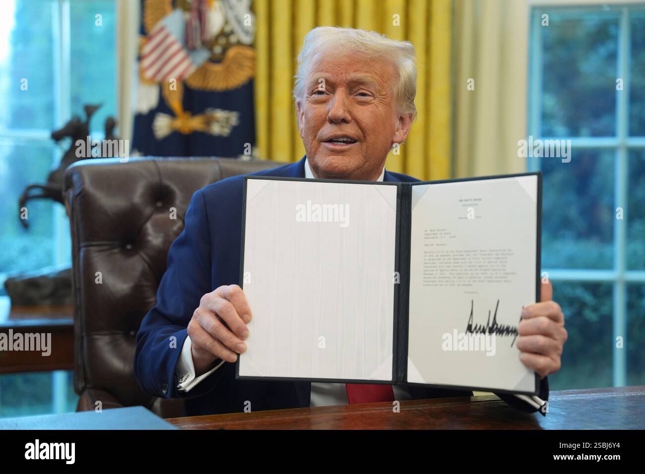 President Donald Trump holds a signed executive order in the Oval ...
