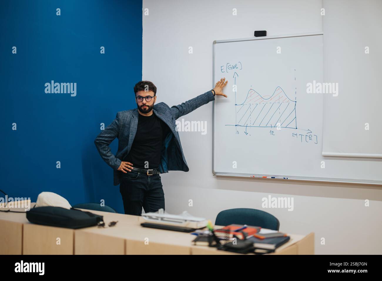 Confident teacher explaining graph on whiteboard in classroom Stock ...