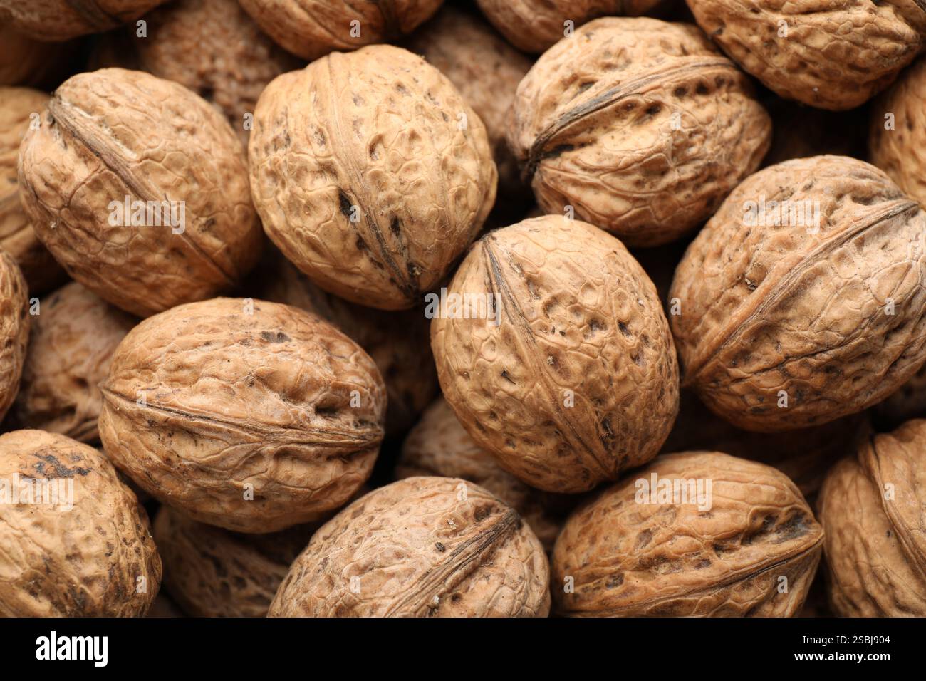 Fresh walnuts in shells as background, top view Stock Photo - Alamy