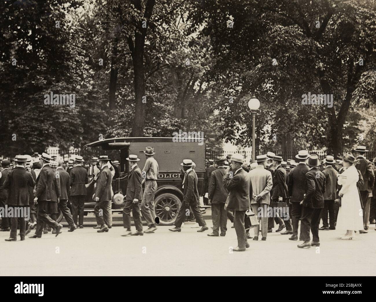 Crowds of people outside around a police wagon watching as the police ...