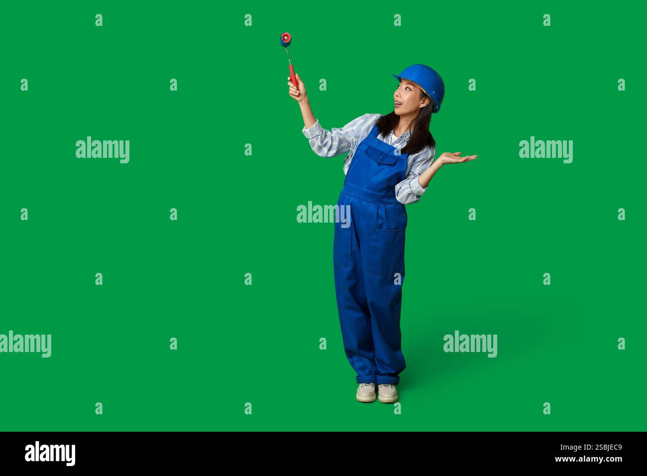 Female Asian shocked painter with roller on green background Stock ...