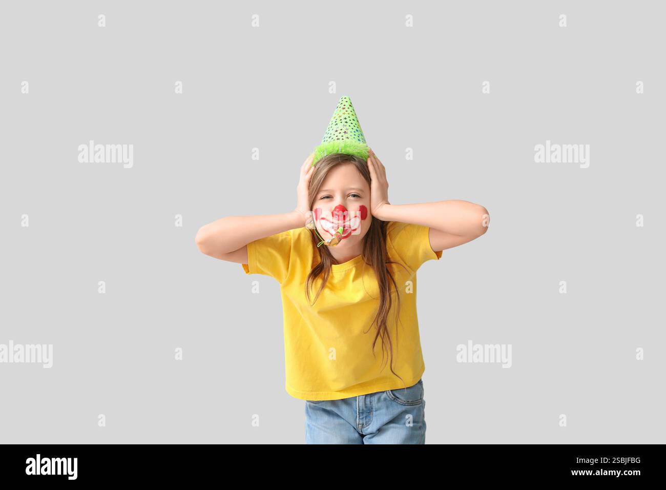 Funny girl with clown makeup, party hat and whistle covering ears on ...