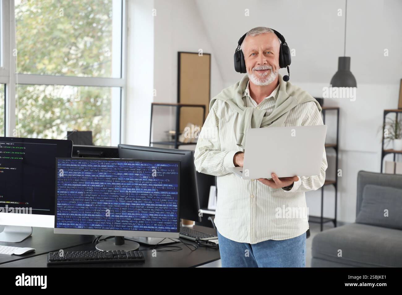 Mature programmer in headphones working with laptop at office Stock ...