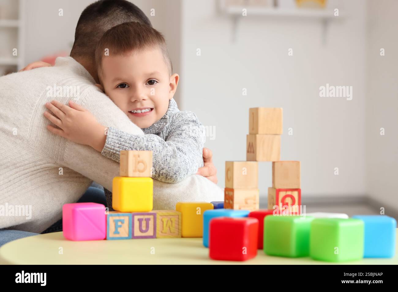 Happy little boy and his father hugging while playing with colorful ...
