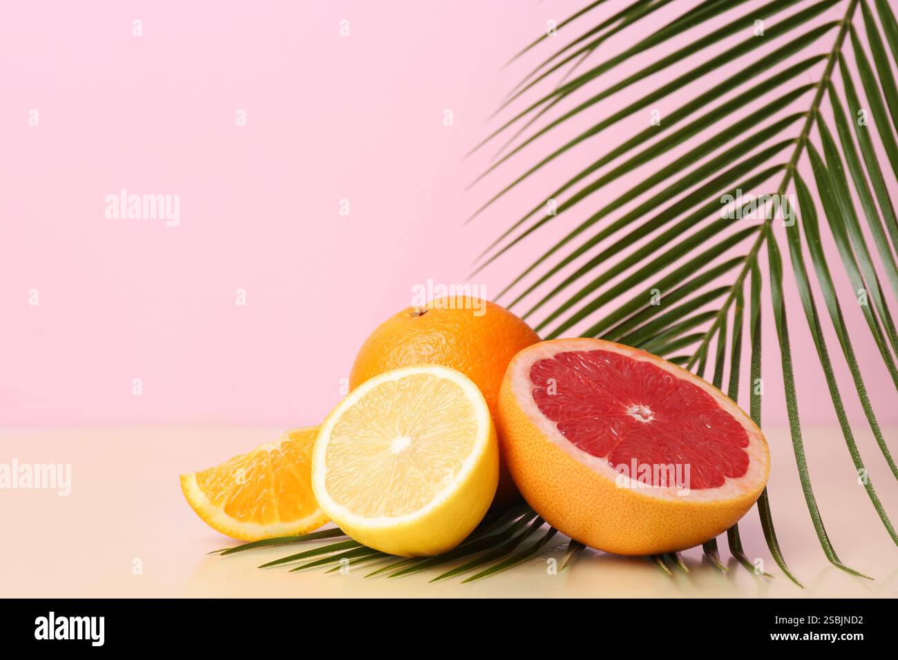 Different cut citrus fruits with palm leaf on color background Stock ...