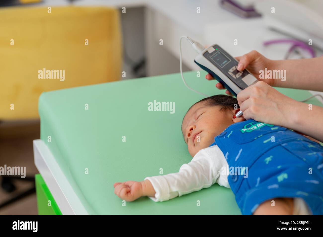 Pediatrician examining newborn baby's hearing with medical device Stock ...