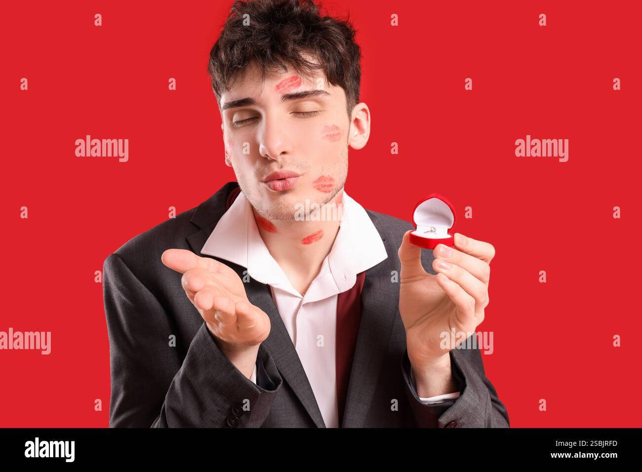 Handsome young man with engagement ring and lips marks on his face ...