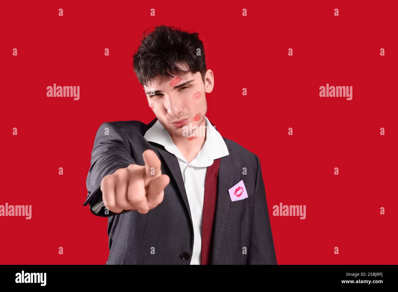 Handsome young man with lips marks on his face blowing kiss against red ...