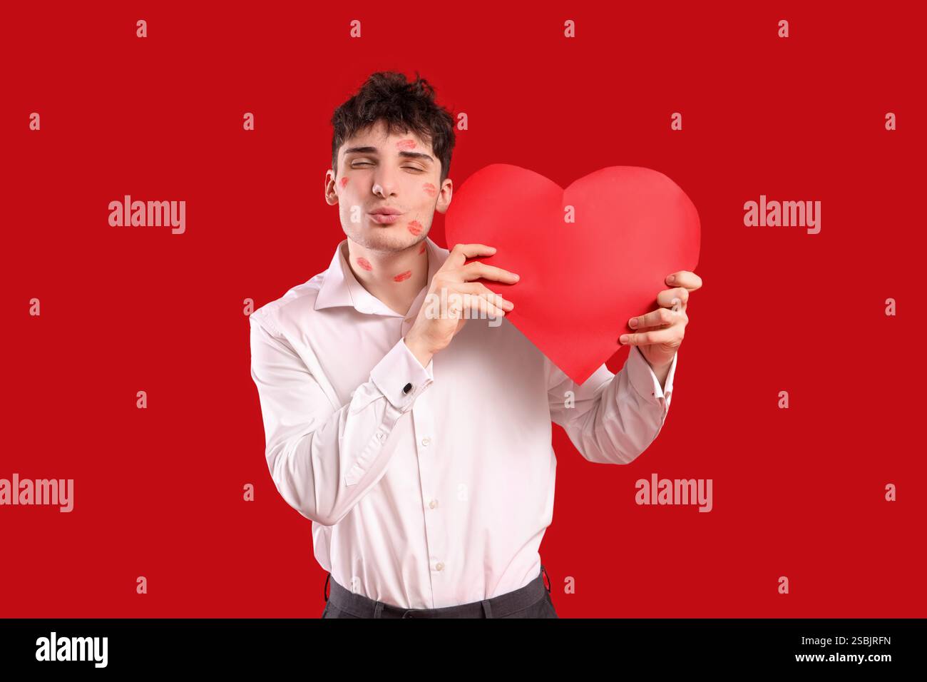 Handsome young man with heart and lips marks on his face blowing kiss ...