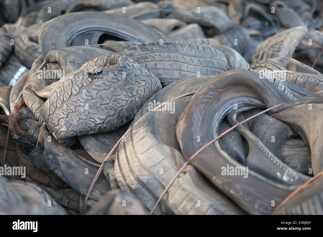 A large pile of worn-out tires in various tread patterns, showing significant wear Stock Photo ...