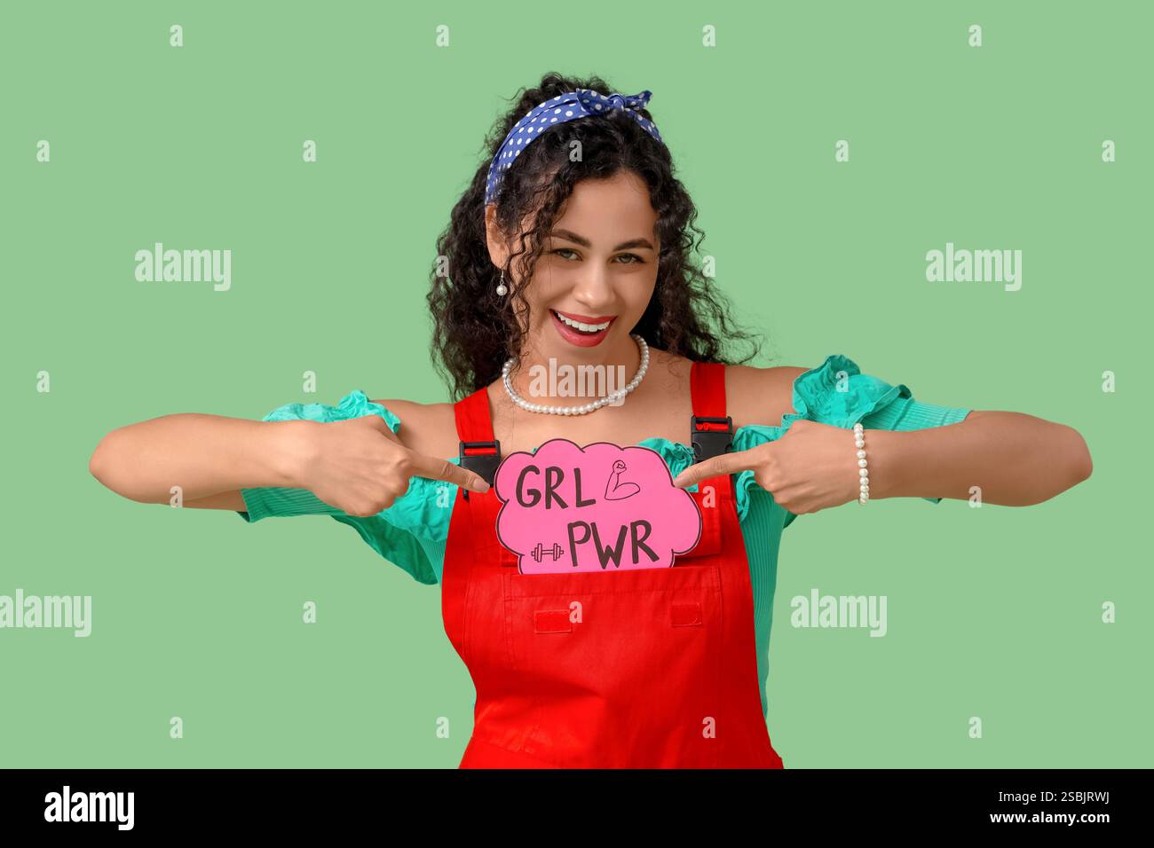 Young African-American pin-up woman pointing at GRL PWR sign on green ...